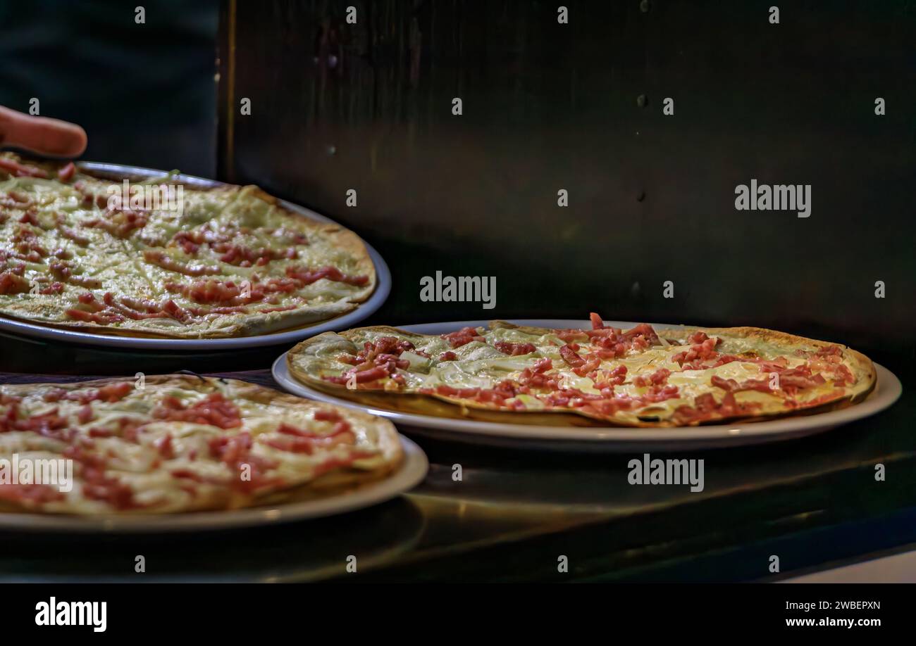 Chef passing flammekueche or tarte flambee with cheese and bacon ...