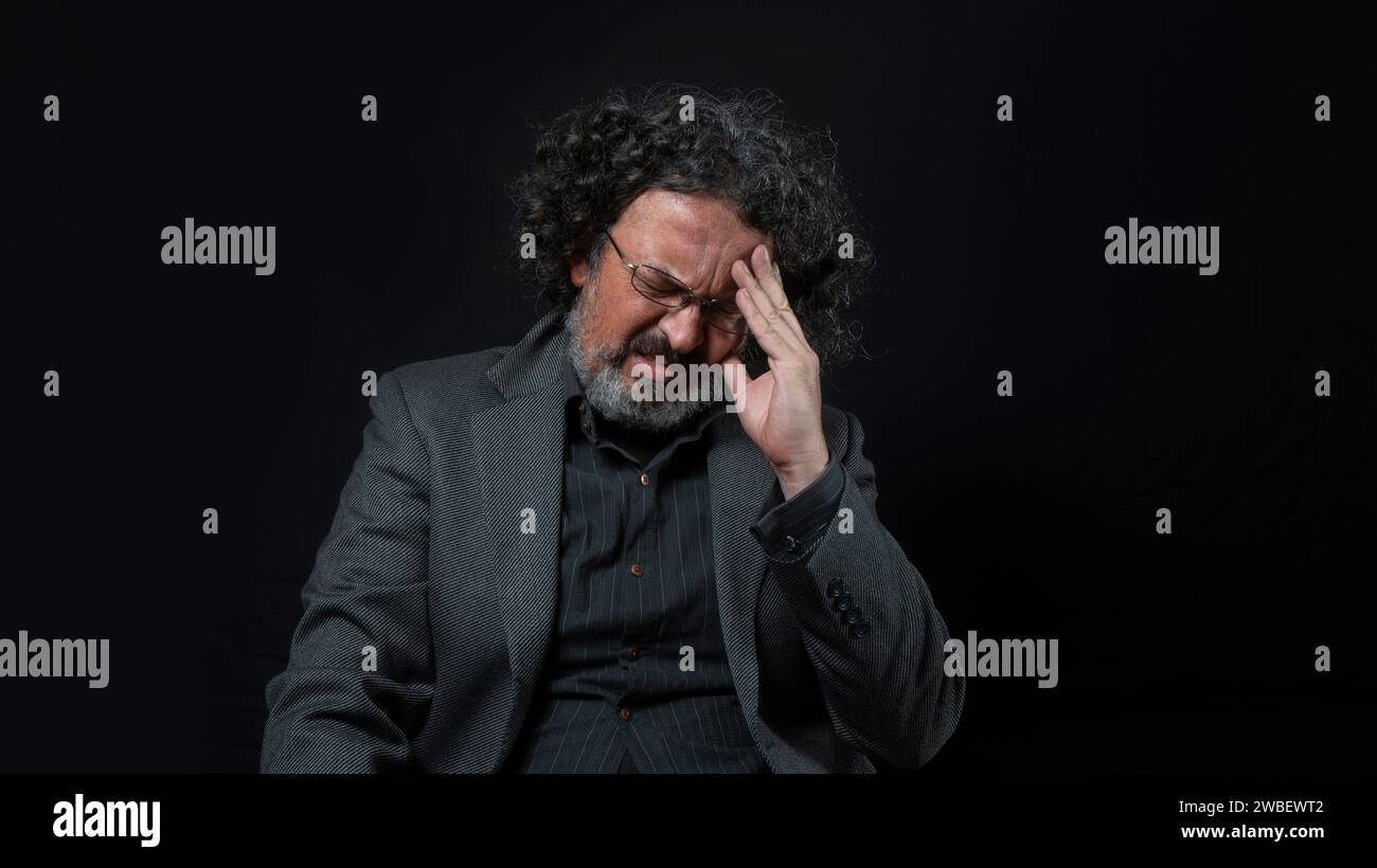 Portrait of latin man with white beard and black curly hair with pained ...