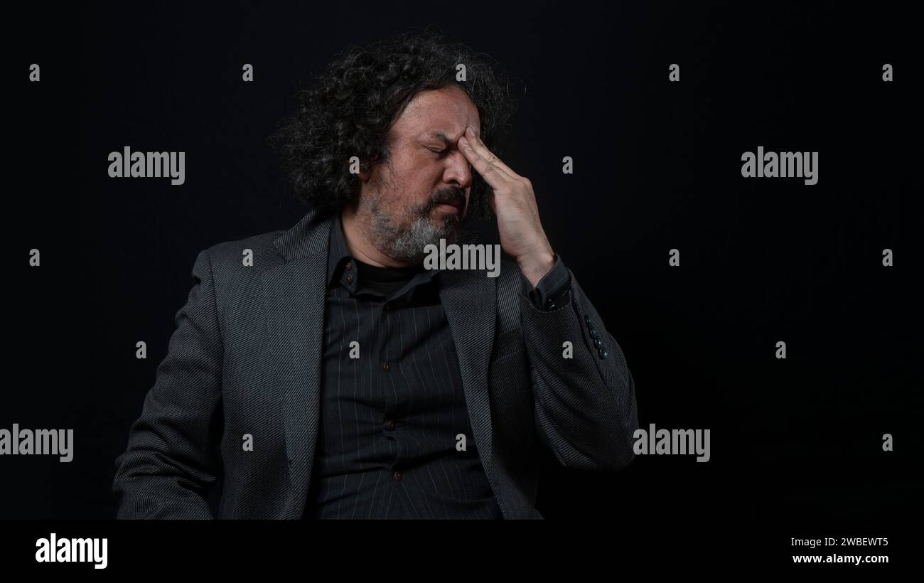 Portrait of latin man with white beard and black curly hair with pained ...