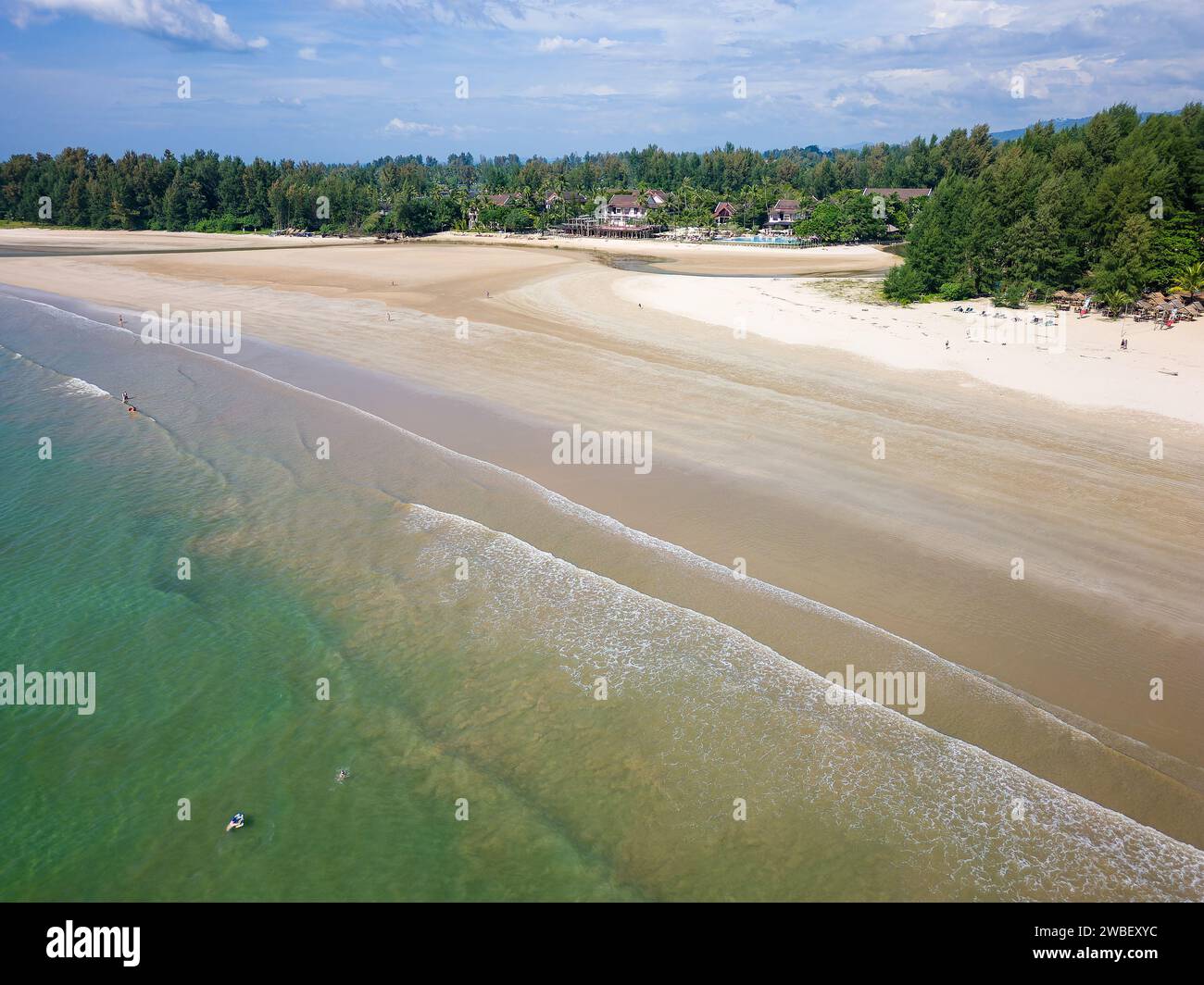 Large, sandy tropical beach and shallow, warm ocean surrounded by lush ...