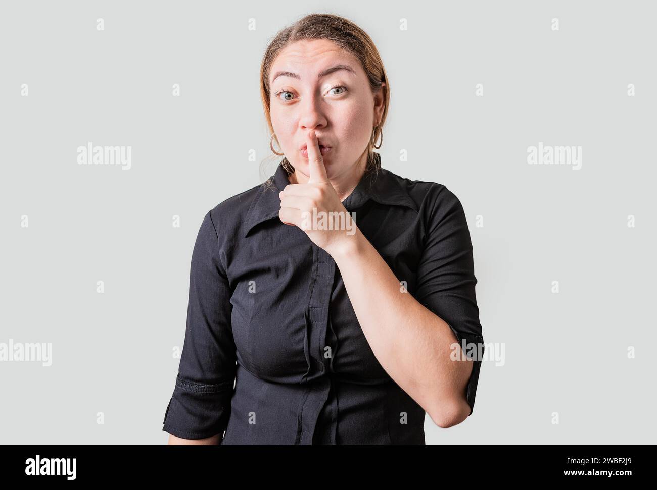 Amazed woman making silence gesture with finger. Blonde girl making ...