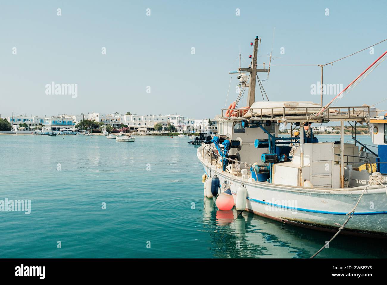 Fishing boat in the port of Antiparos, Greece with the beachfront in ...