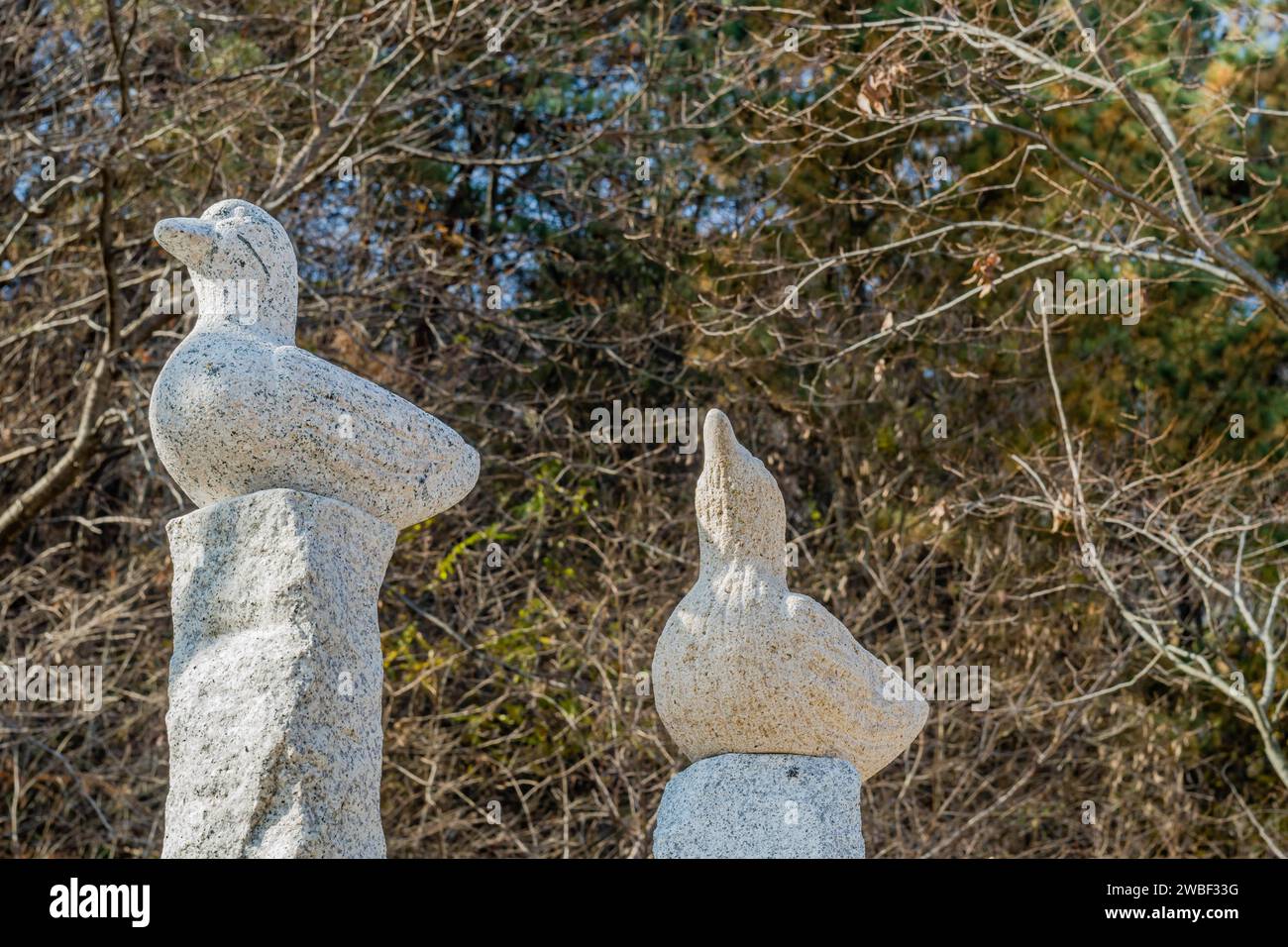 Closeup of stone carved ducks on vertical plinths in wilderness park ...