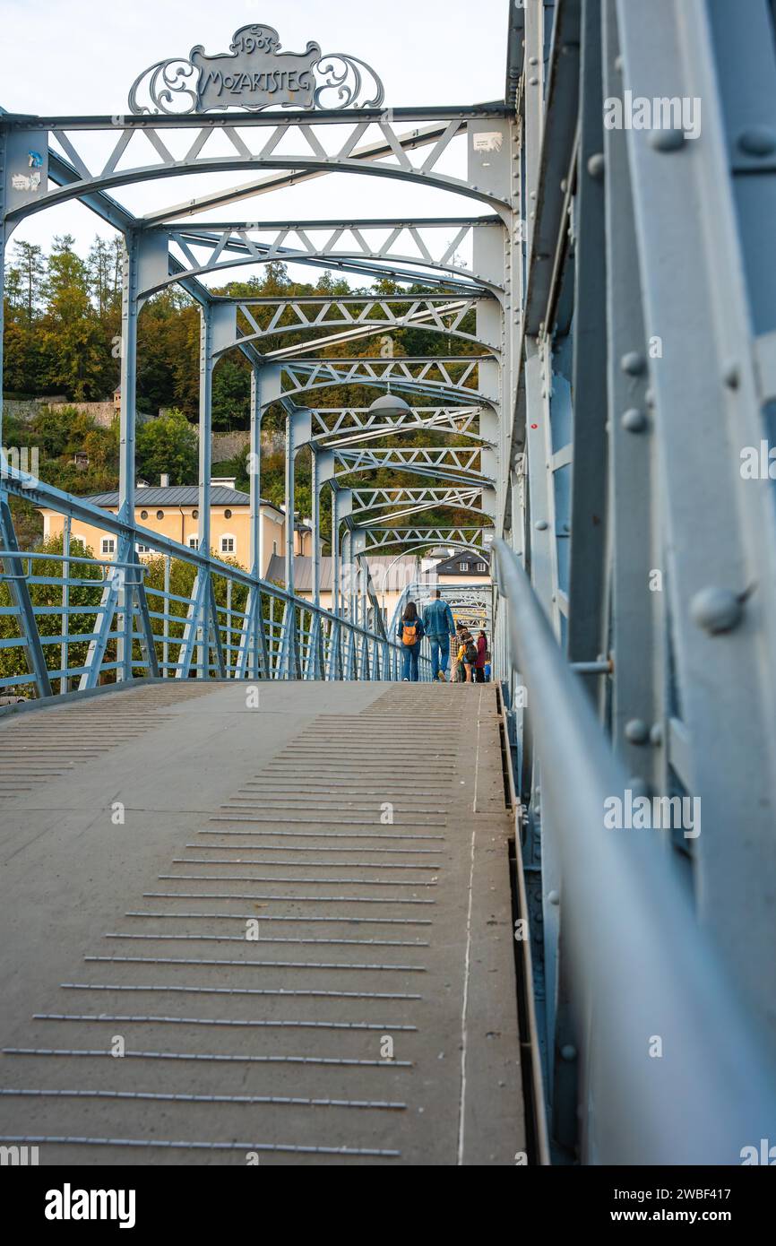 People walking across an ornate steel bridge in an urban area ...