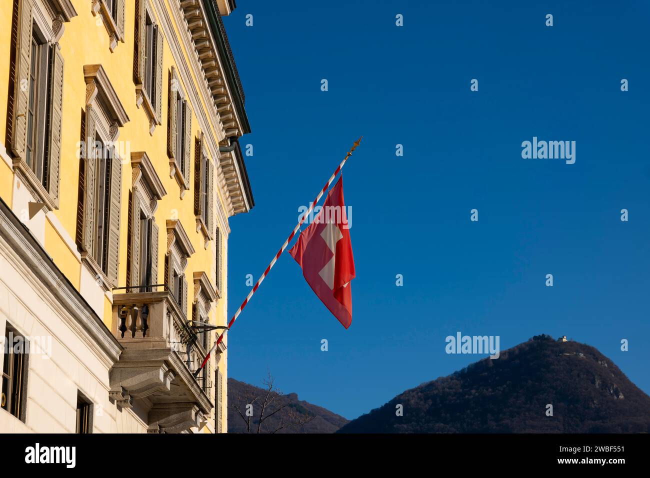 Swiss Flag on City Hall and Mountain Peak Monte Bre Against Blue Clear ...