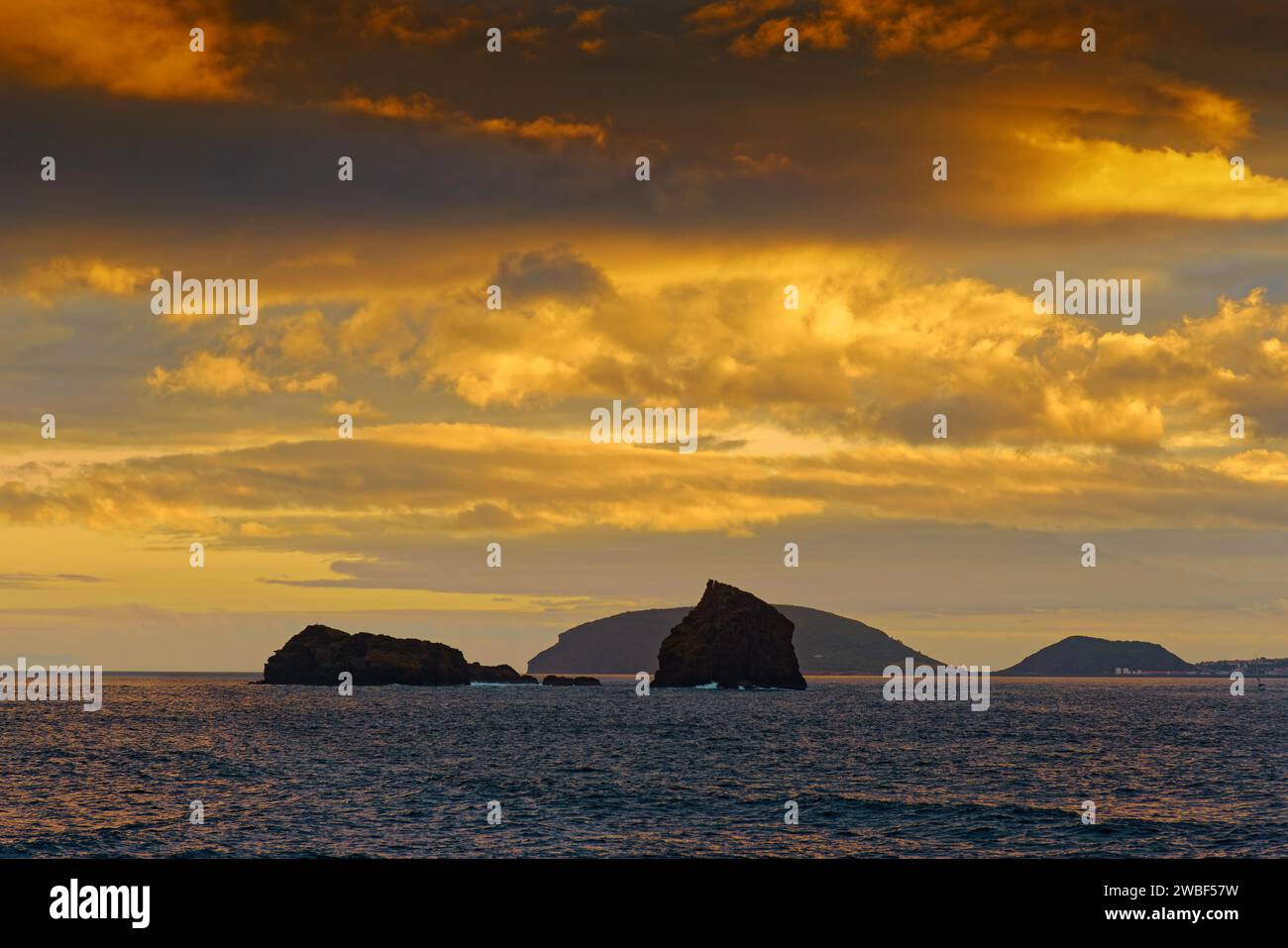 Sea view of the rocks Ilheu em Pe and Ilheu Deitado under an amber ...