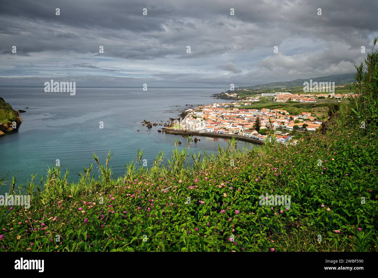 View of the town of Horta surrounded by green hills and cliffs under a ...