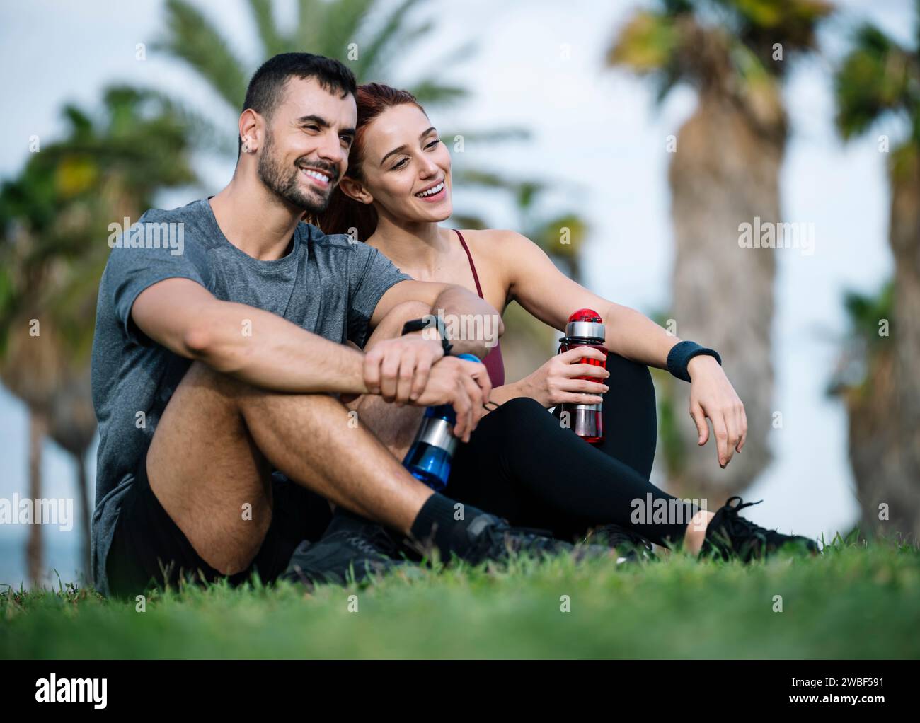 Exhausted young adult couple resting in the floor after running ...