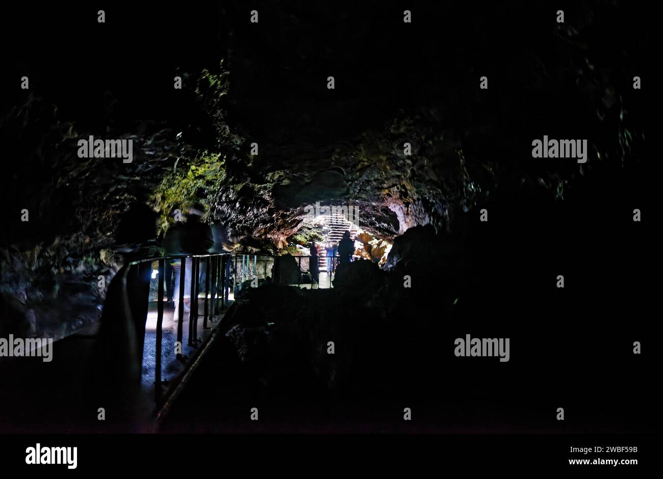 People walking to the cave exit in the lava tunnel Gruta das Torres ...
