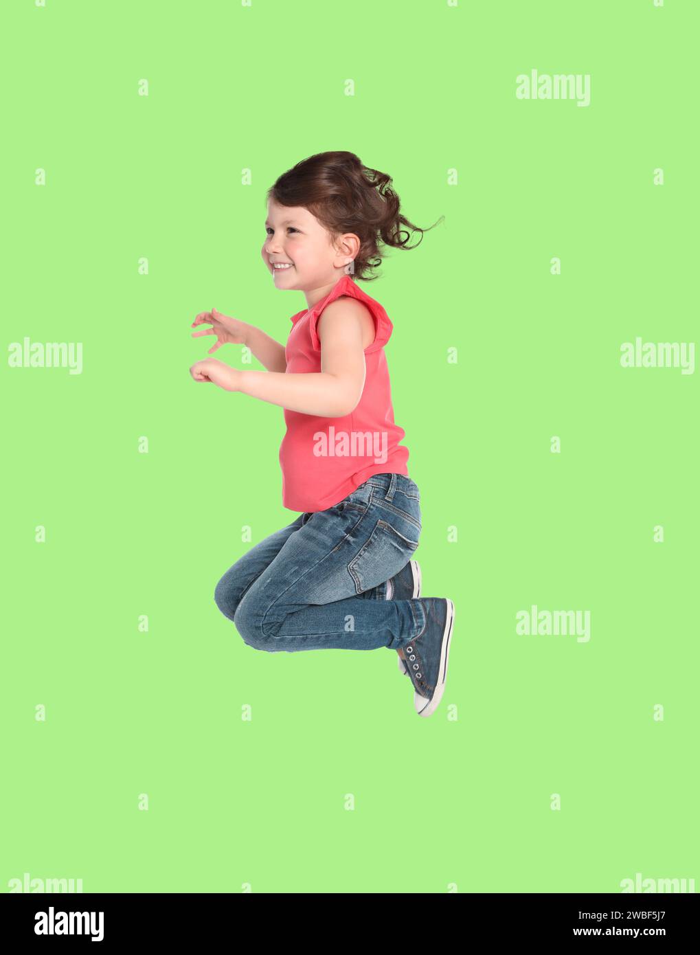 Happy cute girl jumping on light green background Stock Photo - Alamy