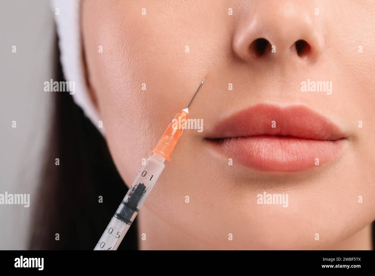 Young woman getting facial injection on light grey background, closeup ...