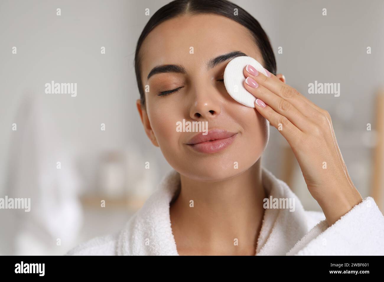 Beautiful woman removing makeup with cotton pad indoors Stock Photo - Alamy