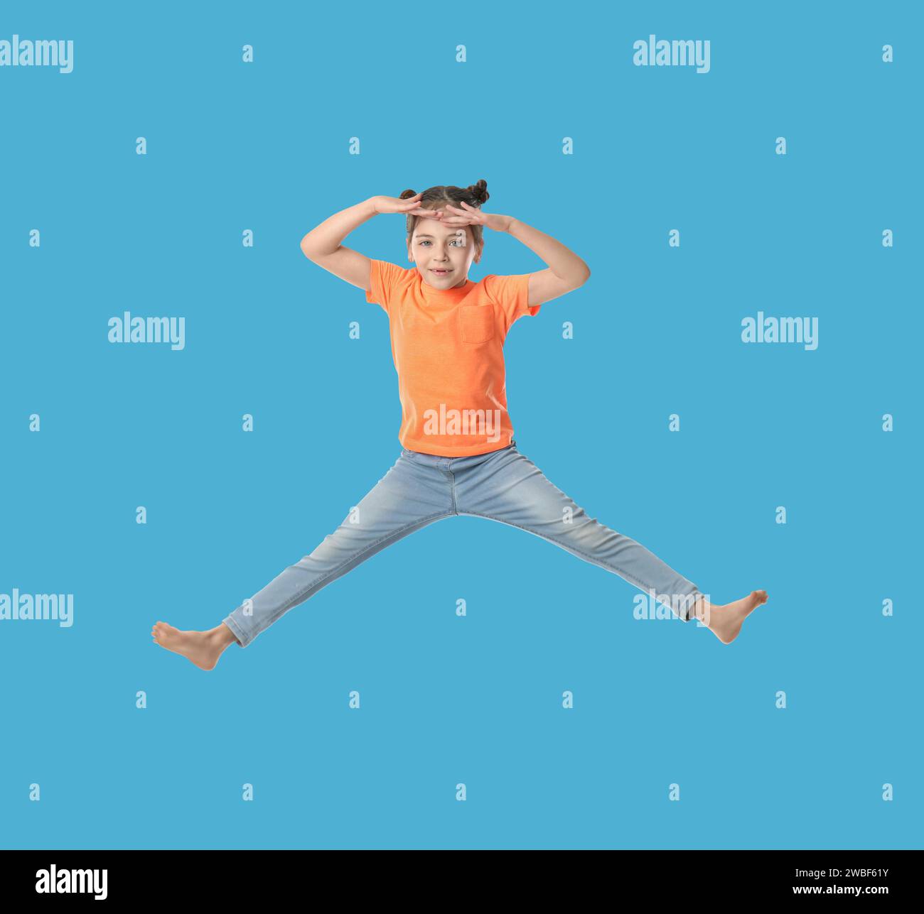 Happy cute girl jumping on light blue background Stock Photo - Alamy