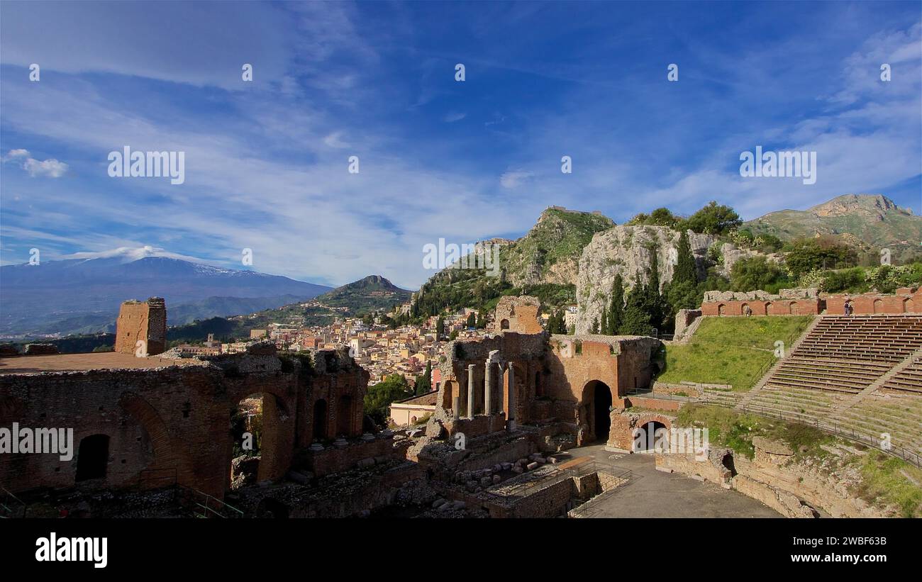 Ancient amphitheatre with ruins in front of a city silhouette and Mount ...