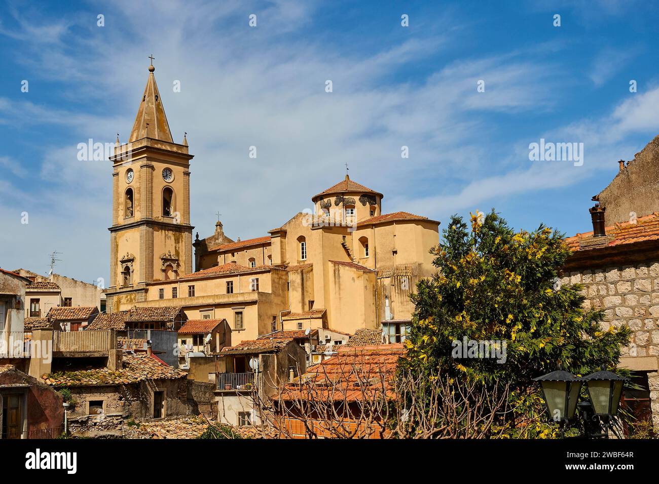 View over the roofs of an old town with church and trees under a blue ...