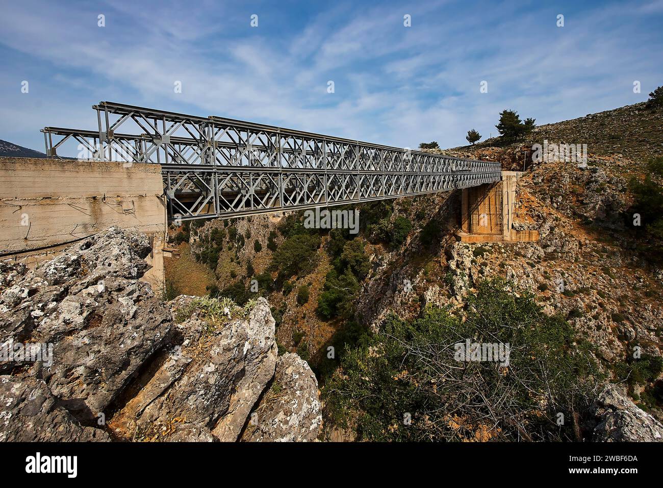 Steel bridge spans a rocky gorge under a blue sky, Aradena Gorge ...