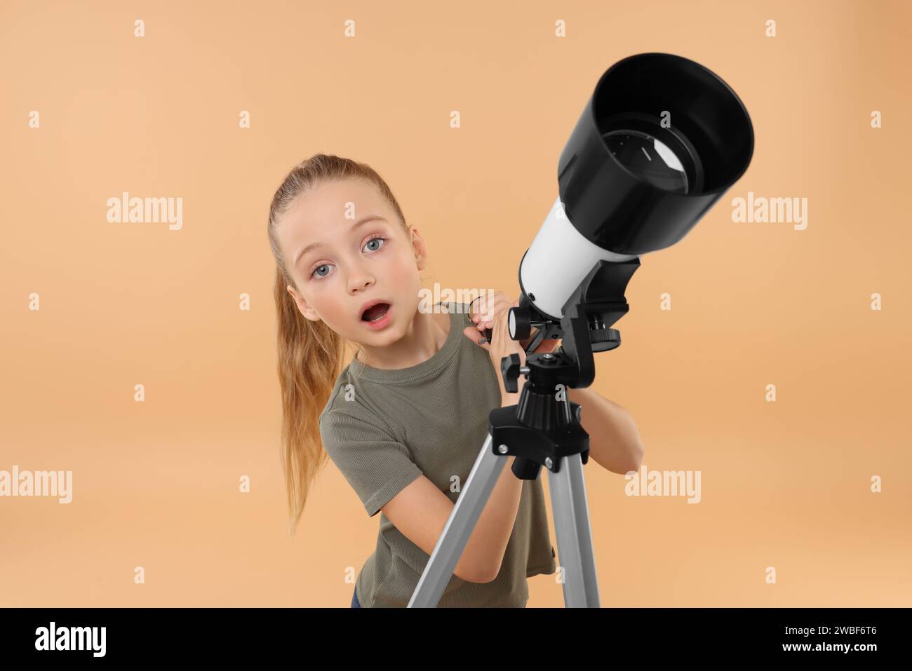 Surprised little girl with telescope on beige background Stock Photo ...