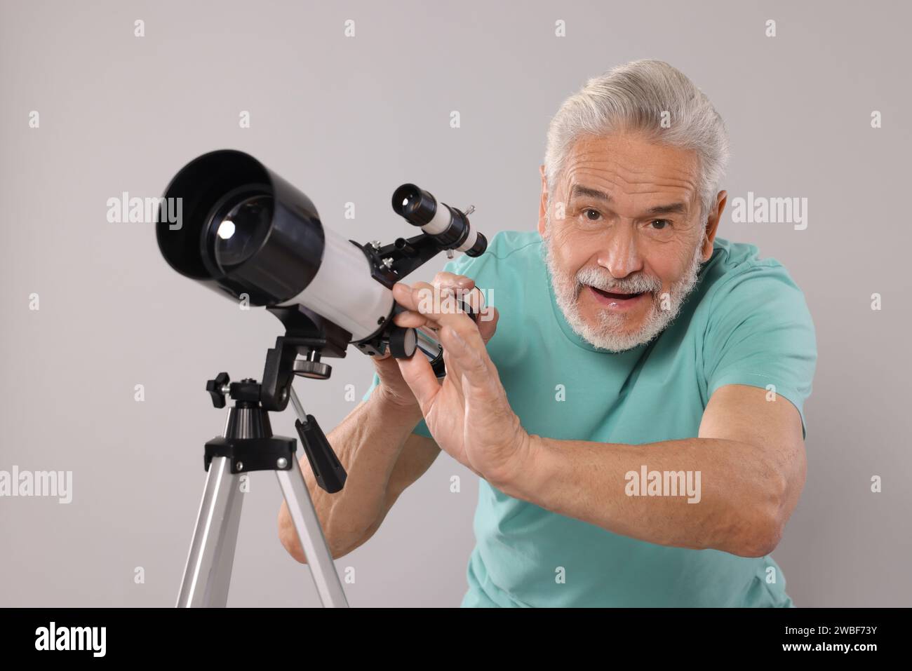 Senior astronomer with telescope on grey background Stock Photo - Alamy