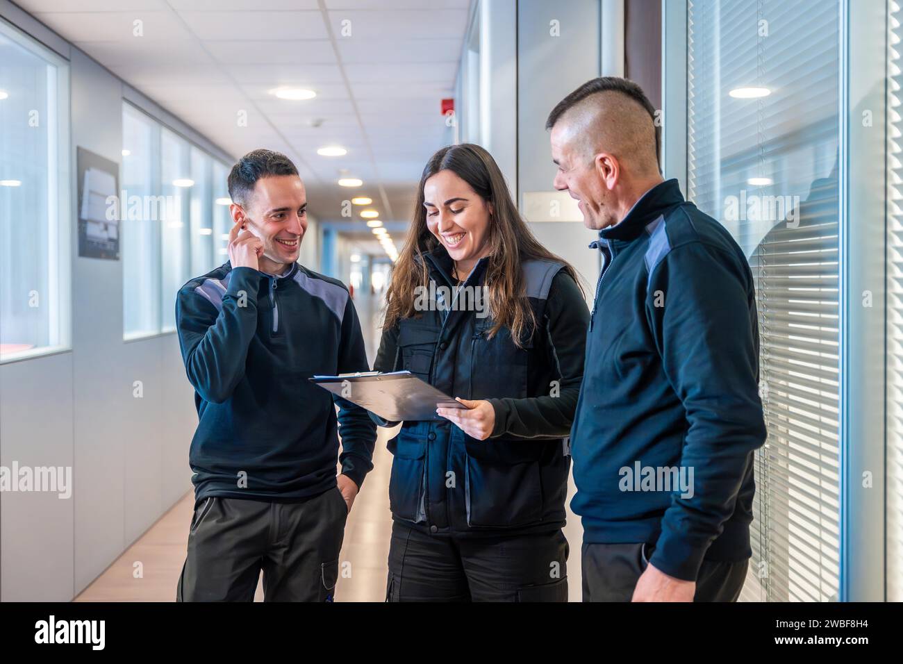 Workers of a logistic factory talking in a corridor holding a folder ...