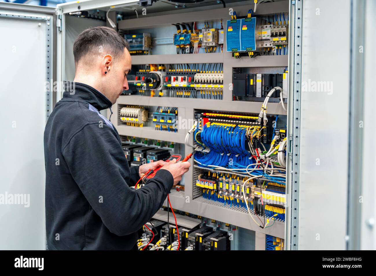 Rear view of a male worker repairing an electrical mechanical system in ...