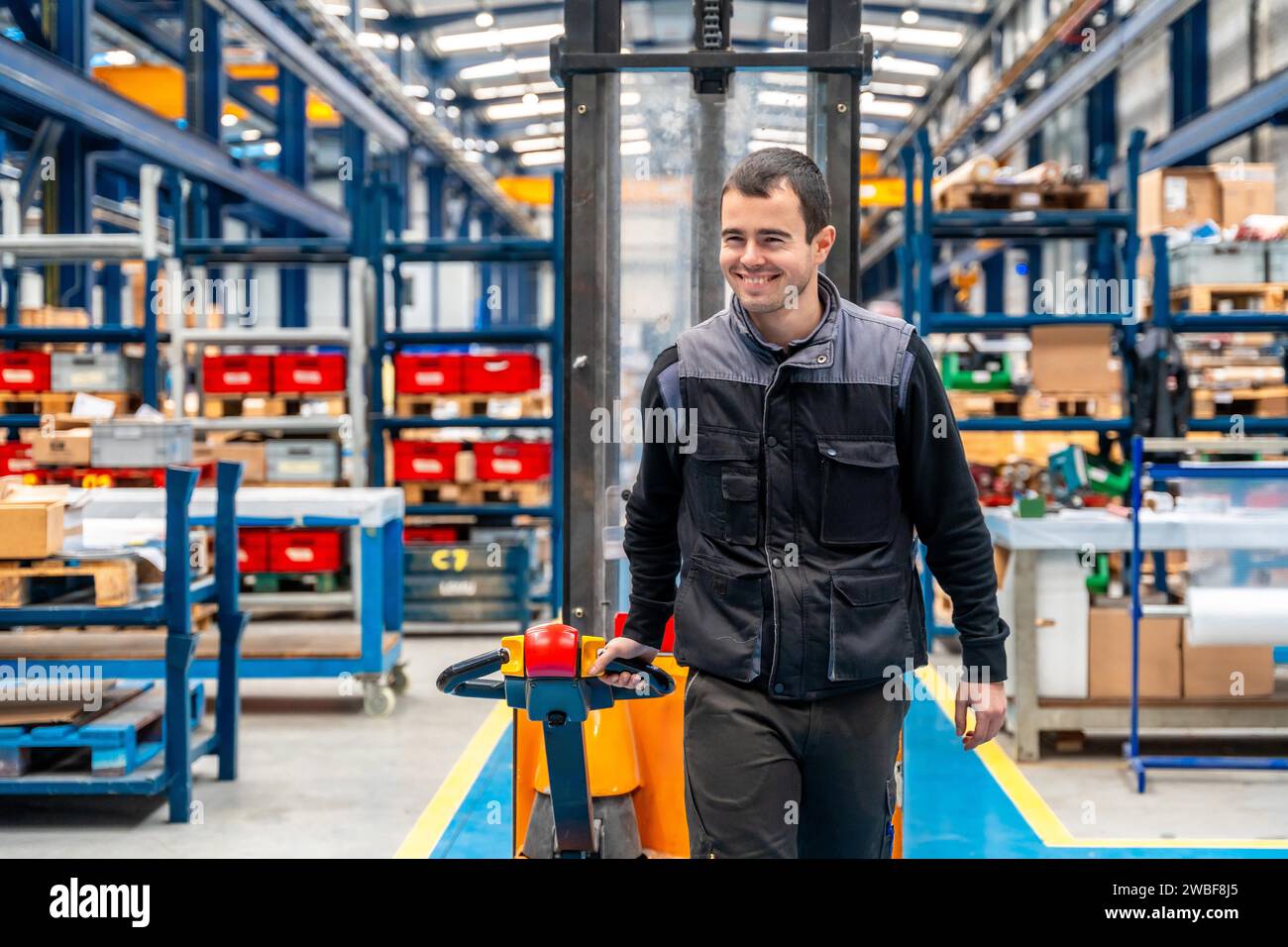 Happy male worker carrying a chart in a corridor of a logistic factory ...