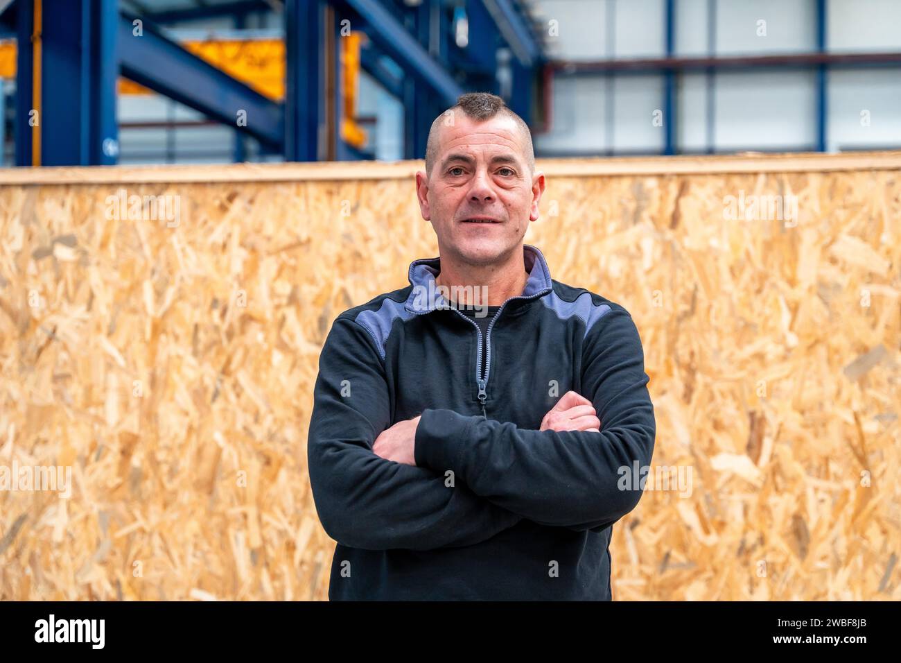 Frontal portrait of an alternative aged worker standing with arms ...