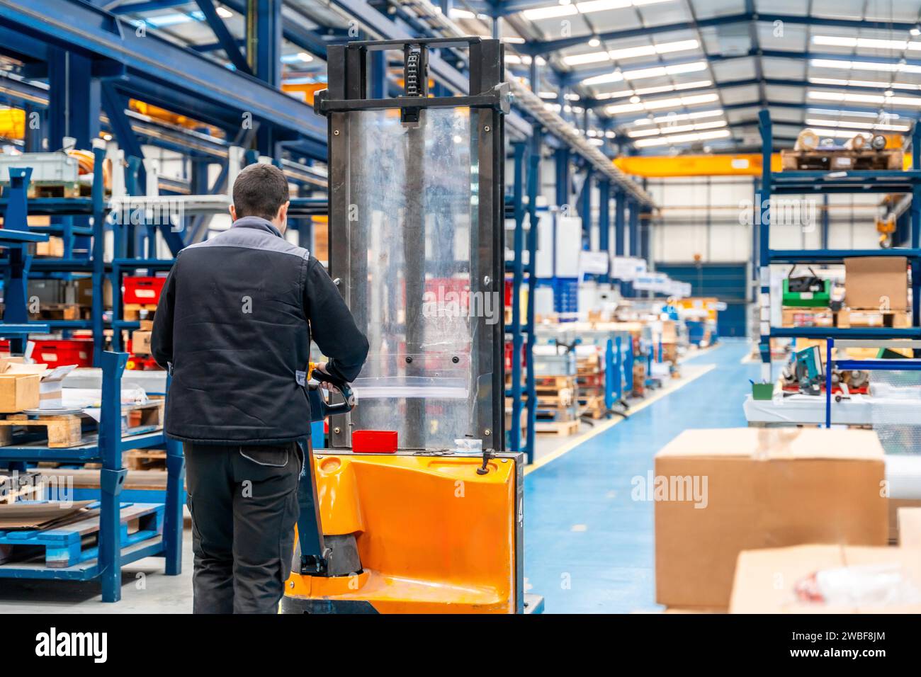 Warehouse worker walking among shelves with handcart in a logistic ...