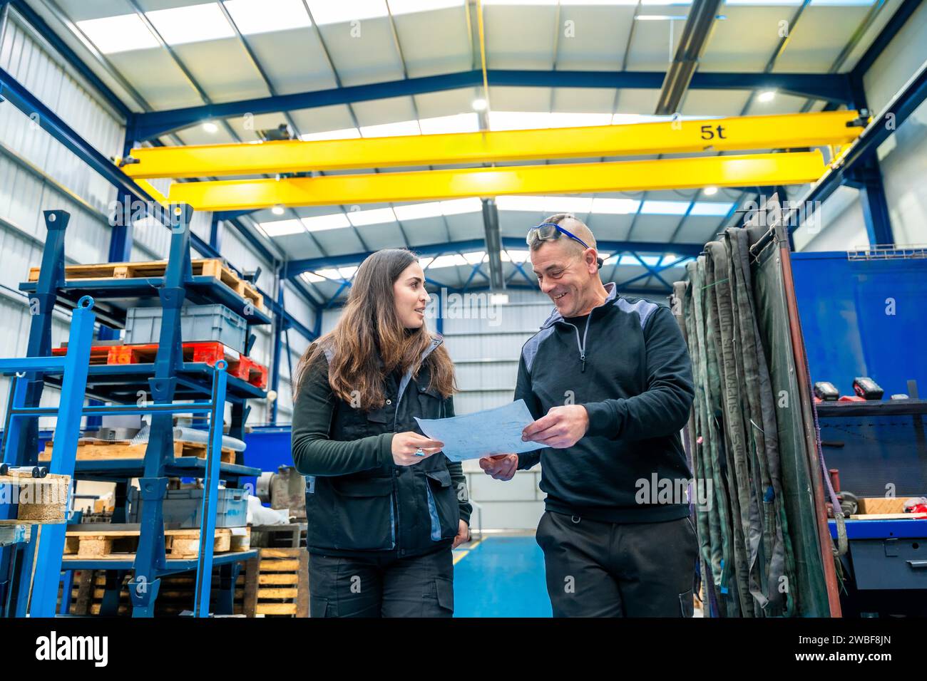 Teamwork of engineers talking and looking at a paper while working in a ...