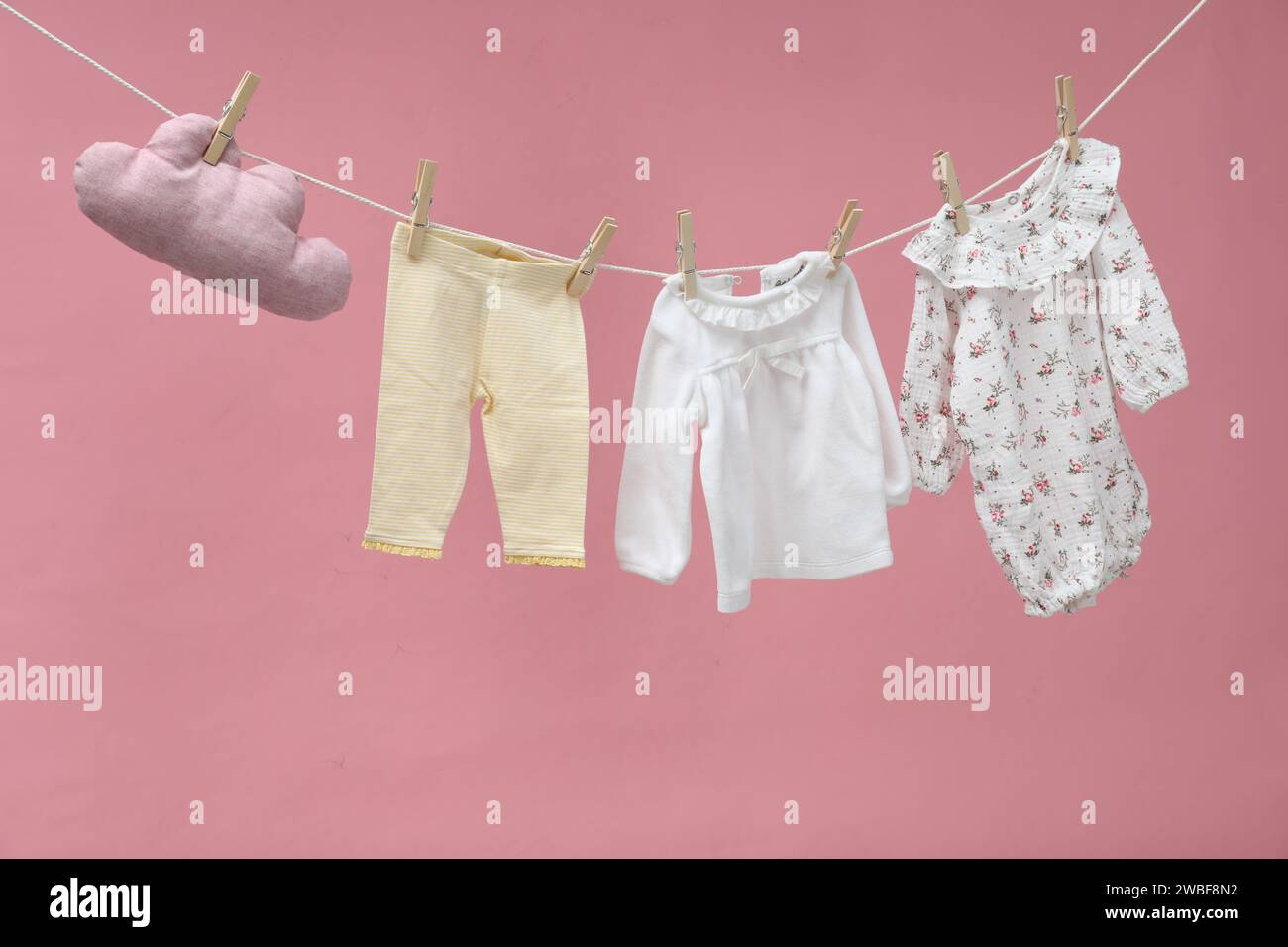 Different baby clothes and cloud shaped pillow drying on laundry line ...