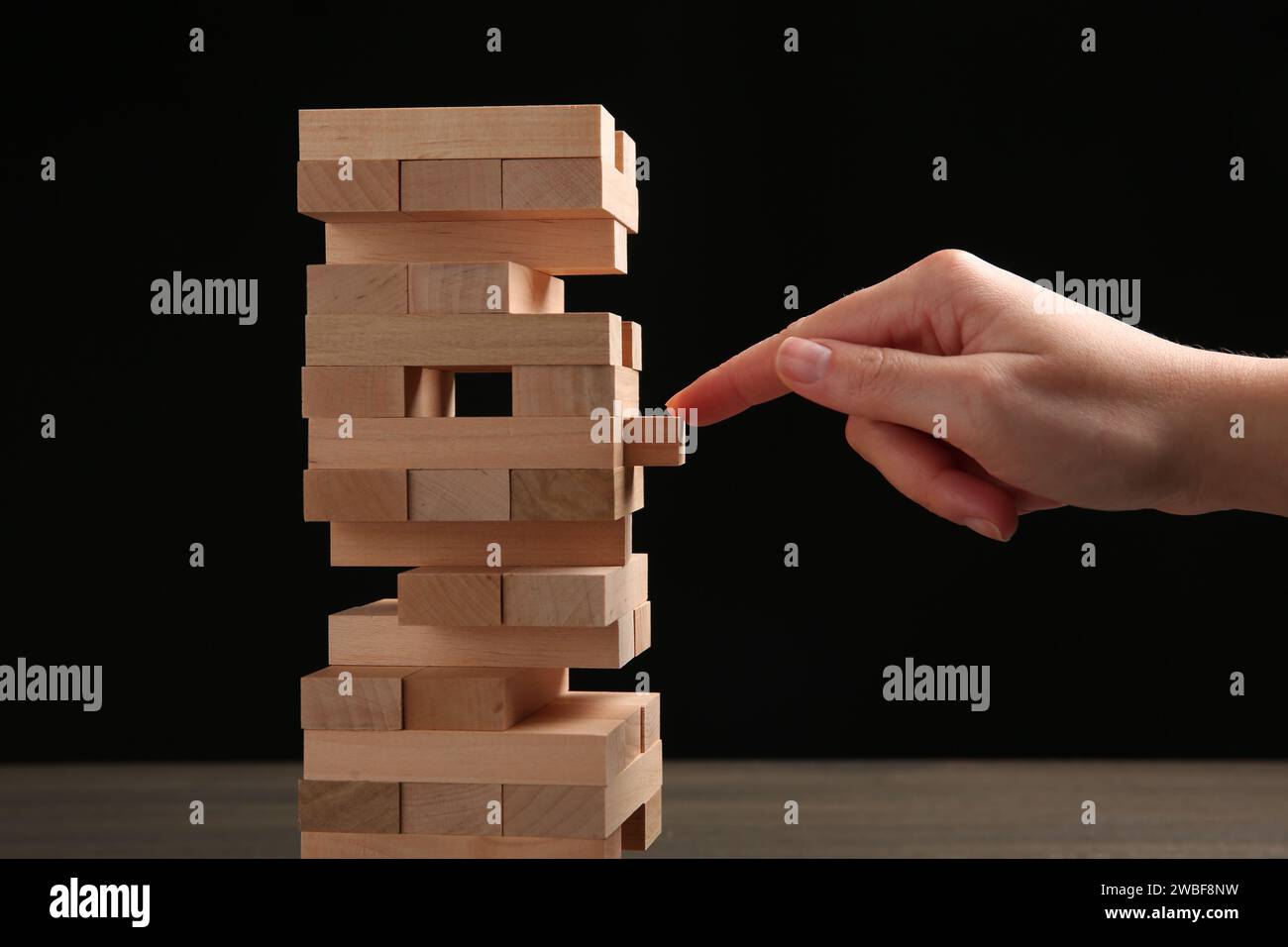 Woman playing Jenga at table against black background, closeup Stock ...
