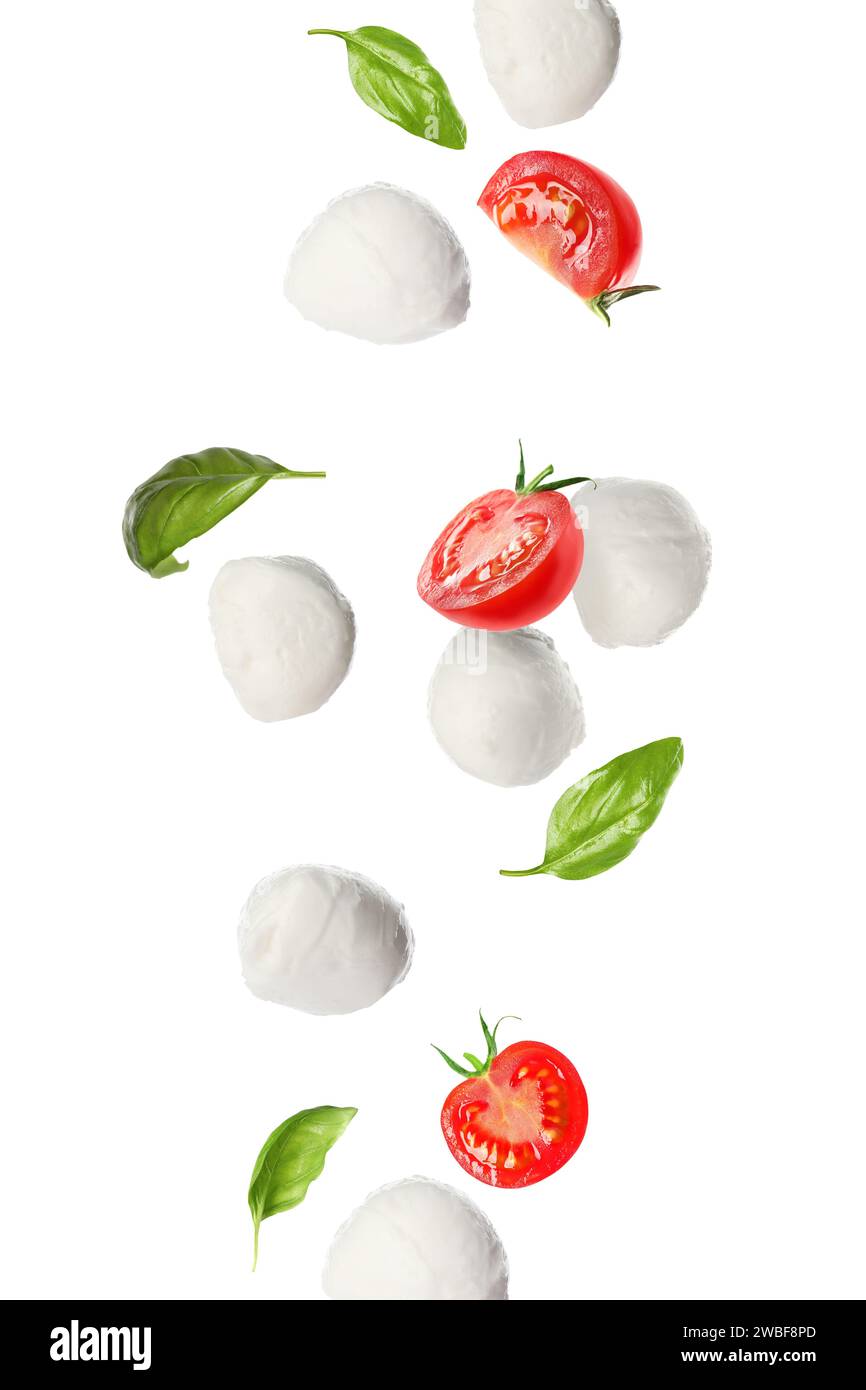 Mozzarella balls, cut tomatoes and basil leaves falling on white ...