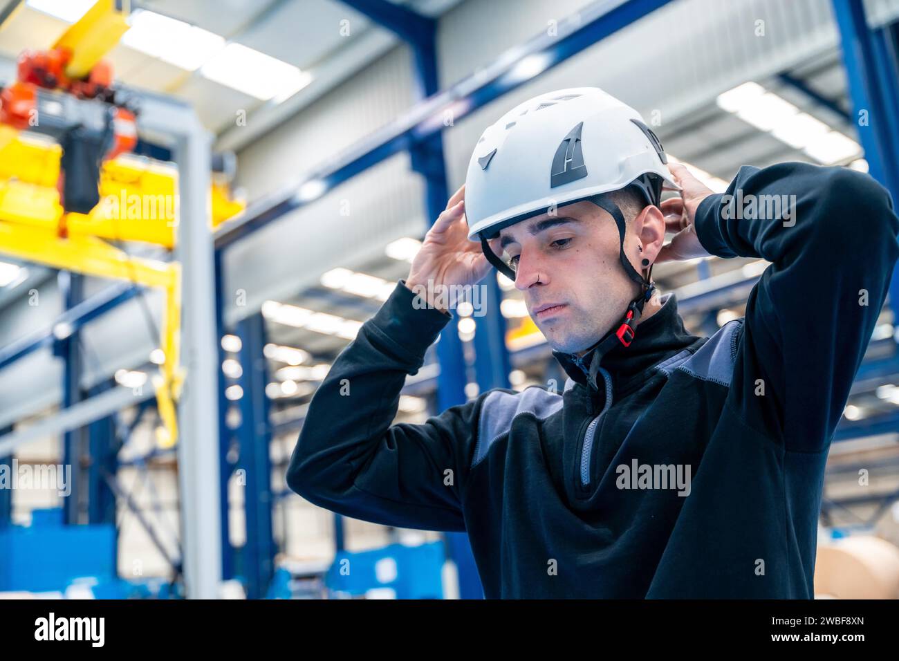 Close-up side view of a worker adjusting helmet in a logistic center ...