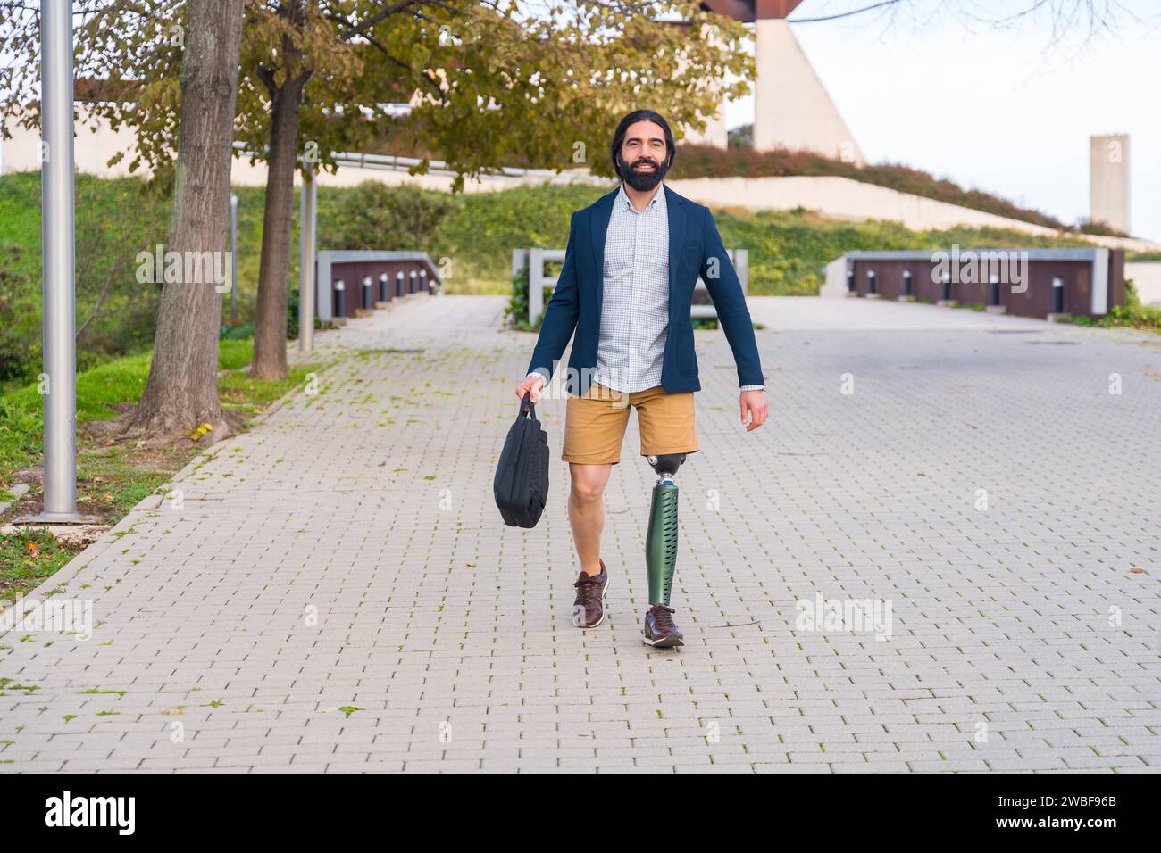 Frontal view of a businessman with prosthetic leg carrying laptop bag ...