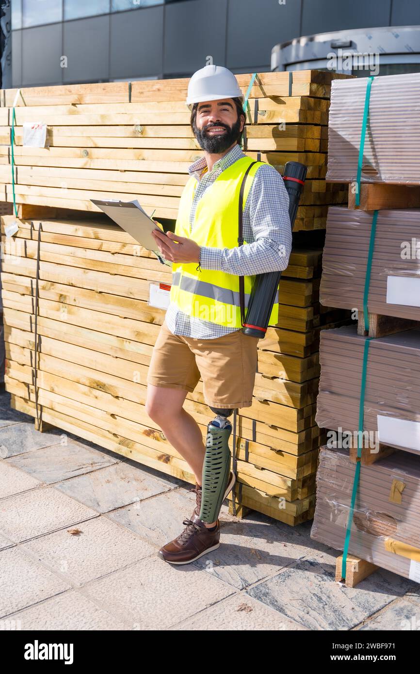 Vertical portrait of a smiley engineer with amputee leg working in a ...