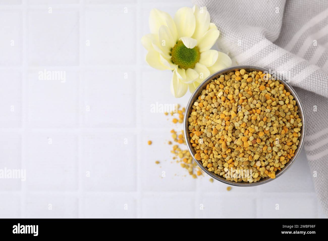 Fresh bee pollen granules and flower on white table, top view. Space ...