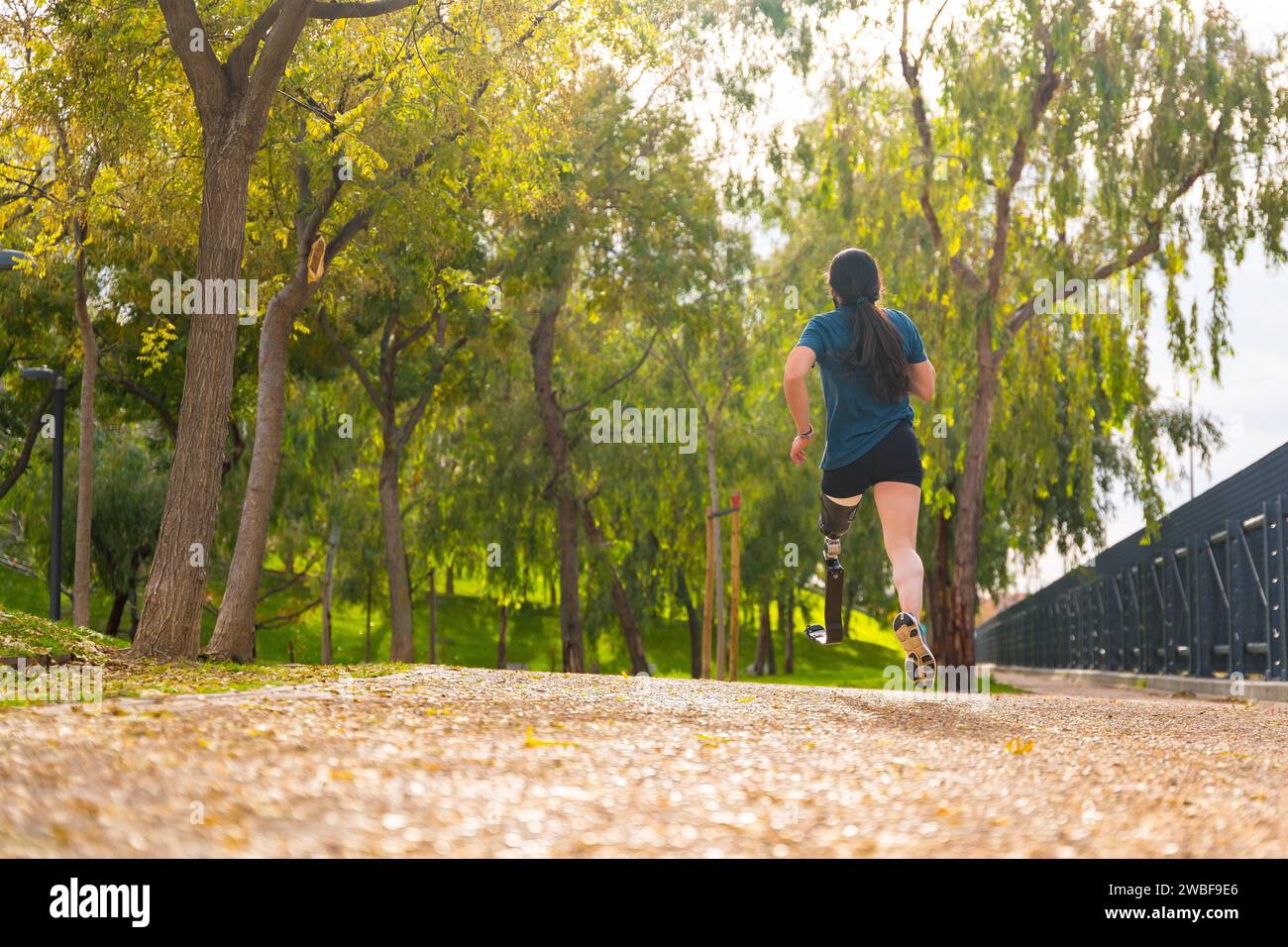 Rear view of an athlete with prosthetic leg running along a park Stock ...