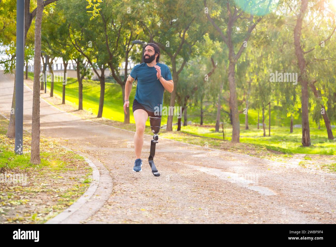 Sportsman with a artificial leg running along a path in an urban park ...