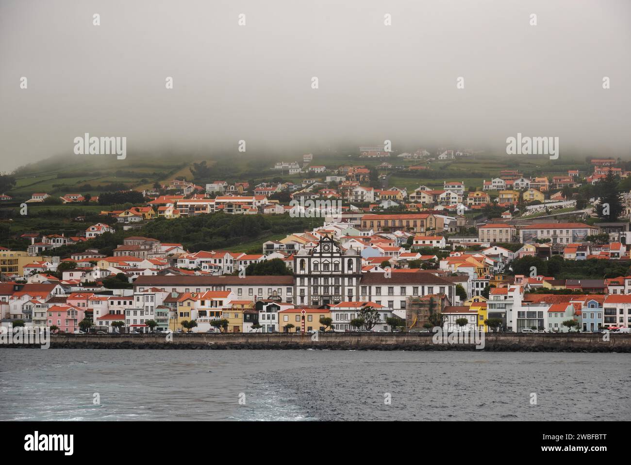 The coastal town of Horta under the fog, colourful houses nestle ...