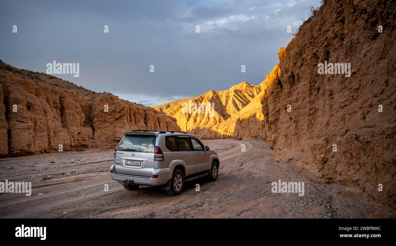Car driving on a winding road in a gorge while the evening sun ...