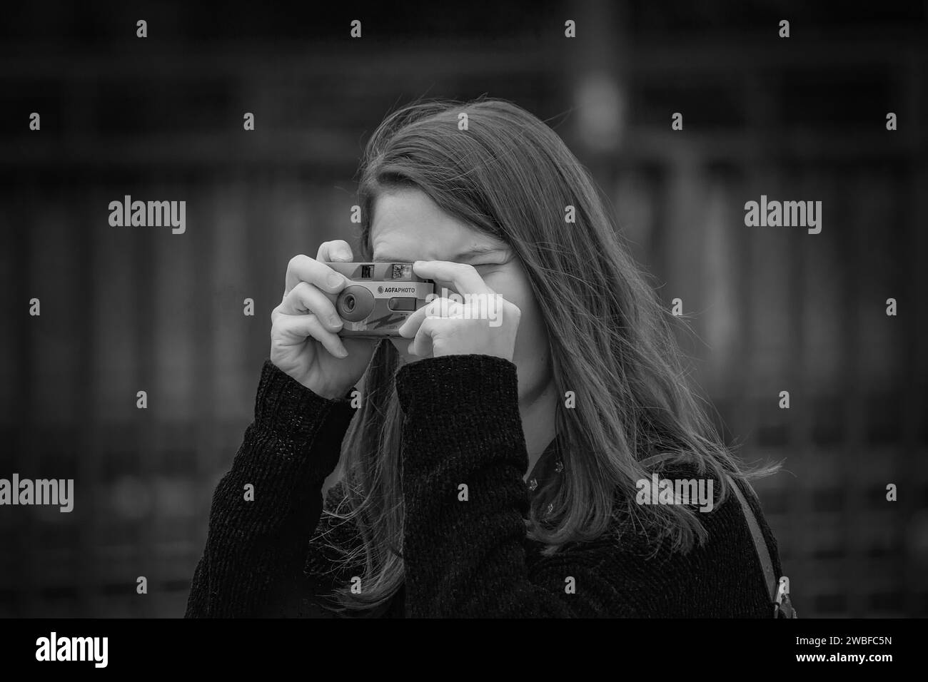 Young woman holds a camera in front of her face and concentrates on ...
