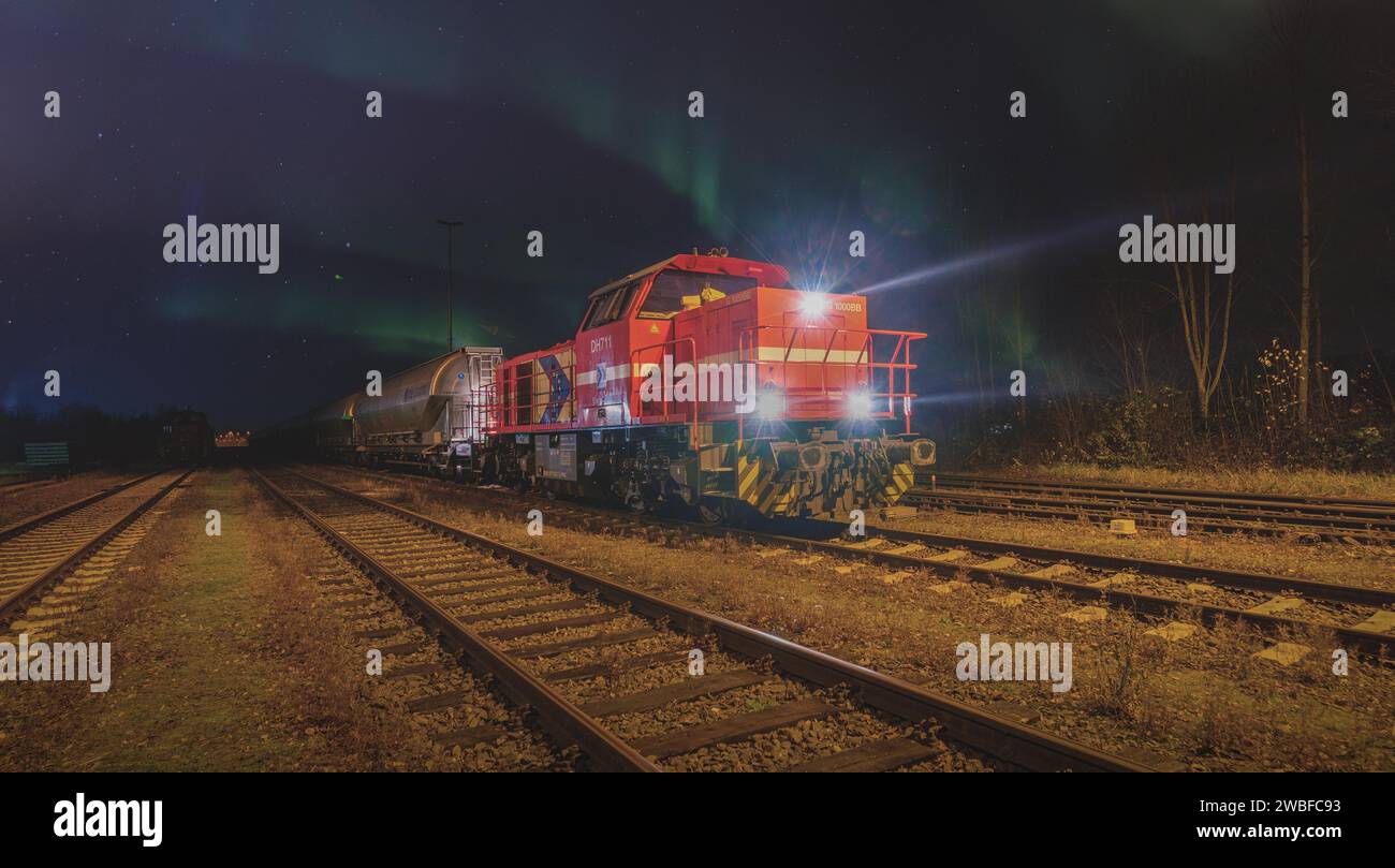 Red locomotive at night with northern lights in the background on an ...