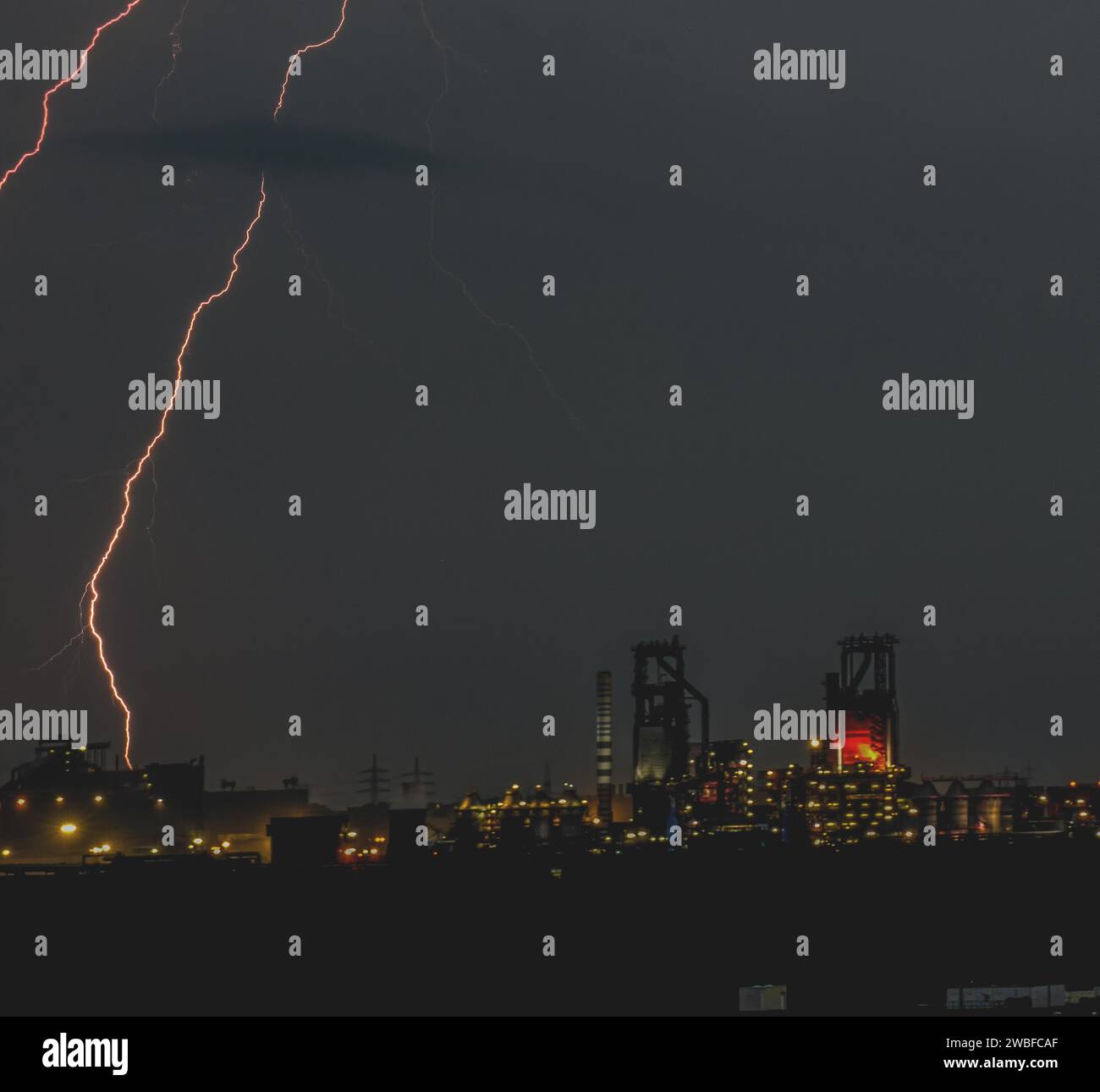 Lightning strikes at night in an urban industrial landscape ...