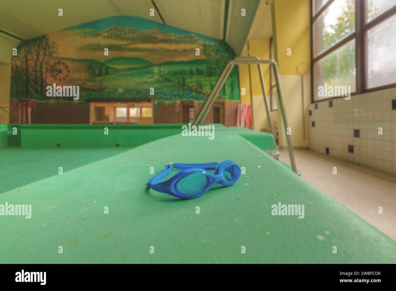 A lost diving diving goggles on a diving board in an empty swimming ...