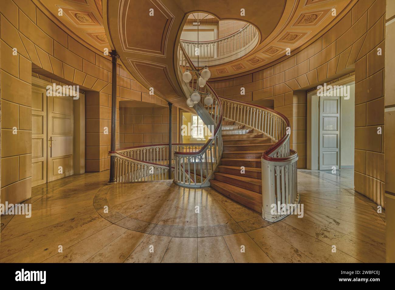 An elegant, curved wooden staircase in a room with natural lighting ...