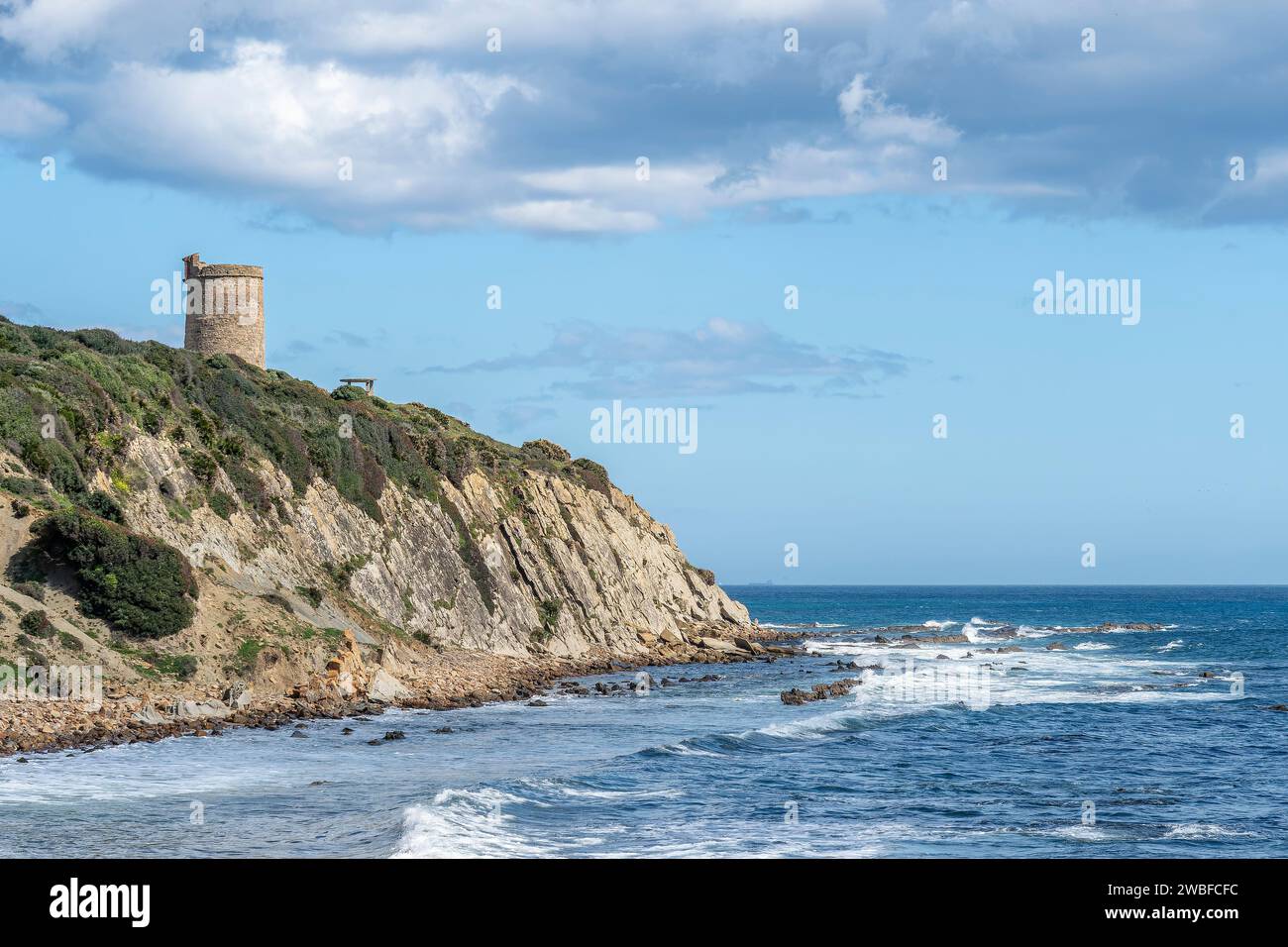 An ancient stone watchtower stands atop a cliff with lush greenery ...