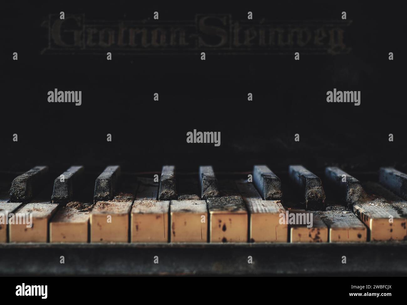 Dusty, worn piano keys of an old Steinway piano in a dark atmosphere ...