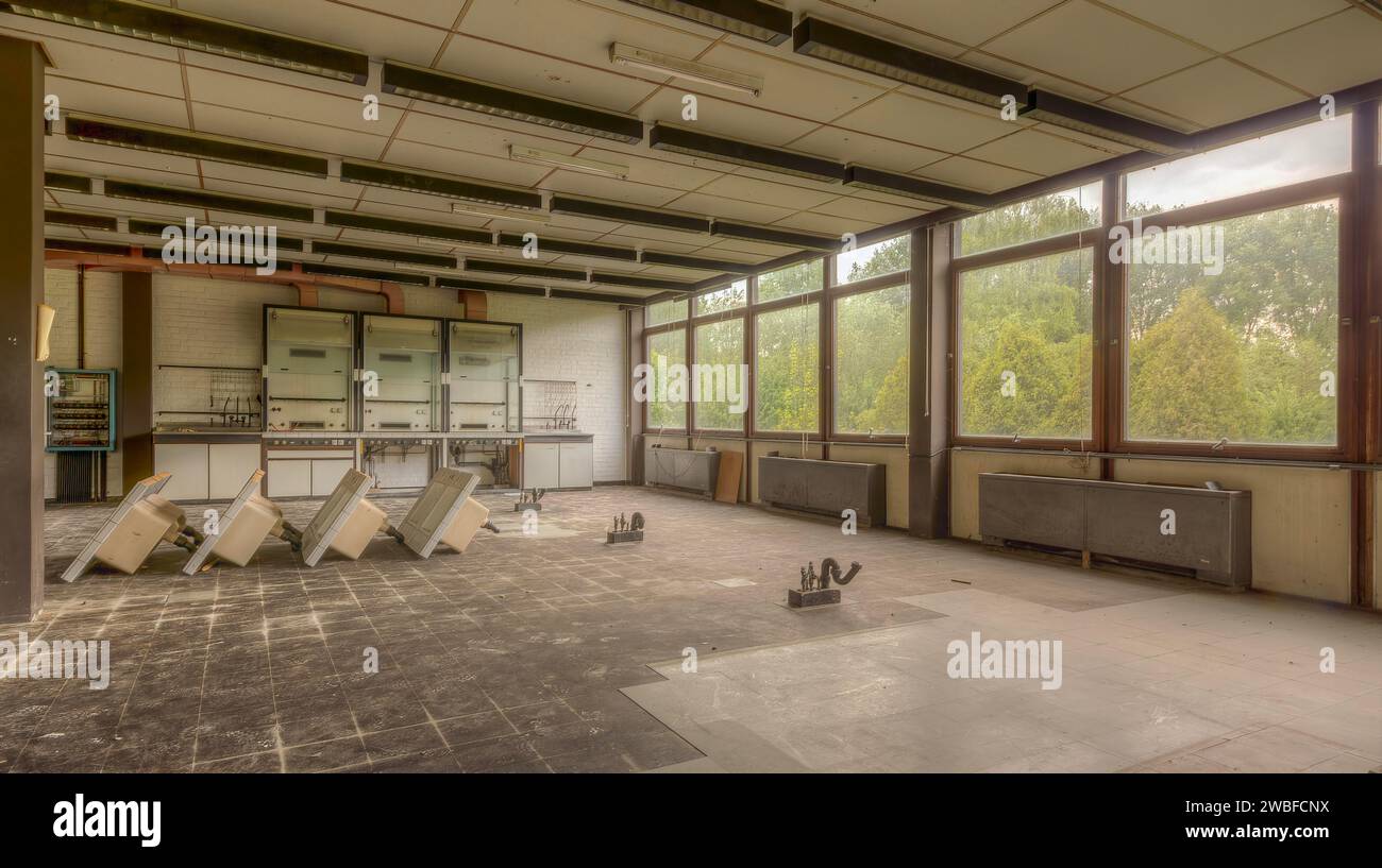 A large empty room with falling ceiling tiles and abandoned lab benches ...