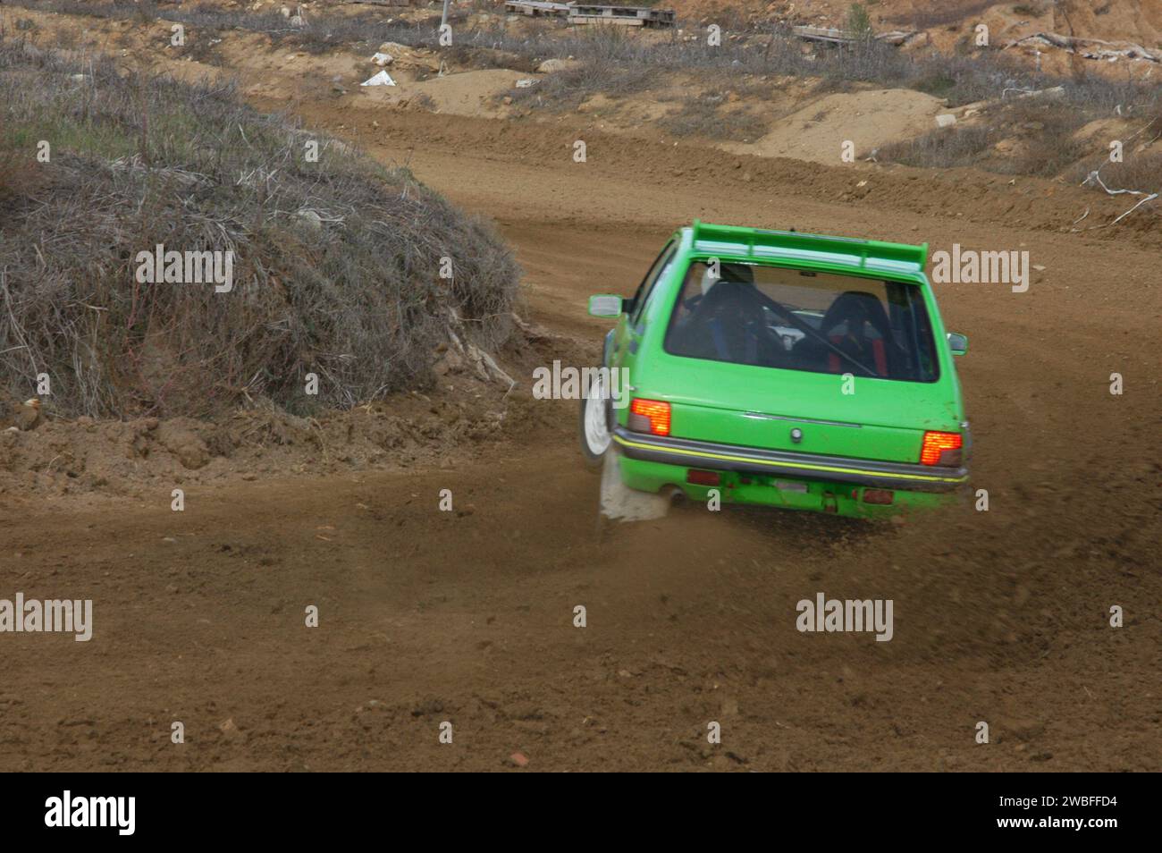 Classic cars gracefully drift around a rally track, swirling dust in a ...