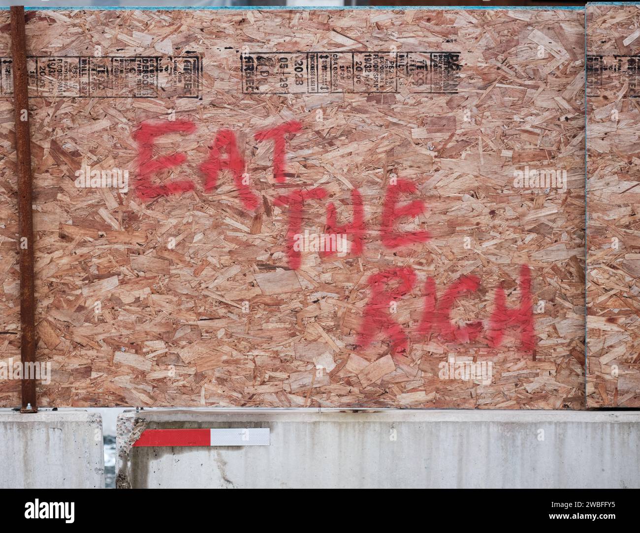 "Eat the Rich" graffiti on the boarded up surrounding construction of ...