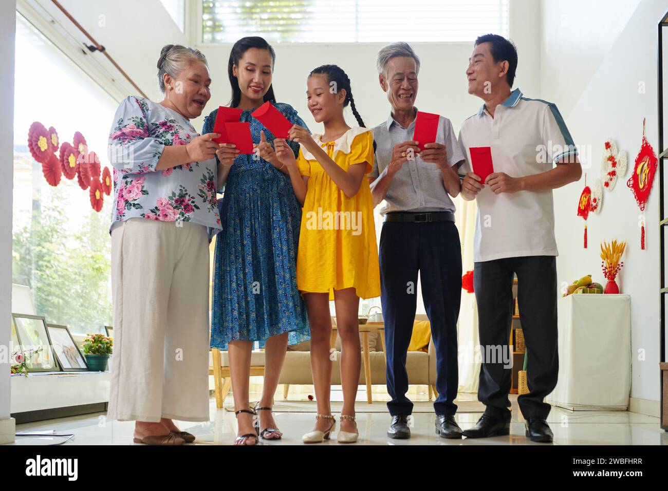 Excited family members exchanging lucky money envelopes when ...